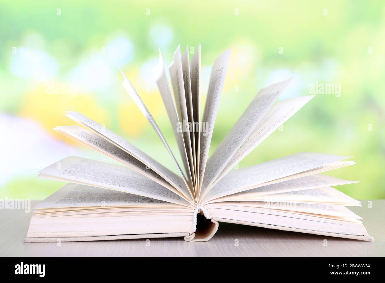 Open book on wooden table on natural background Stock Photo - Alamy