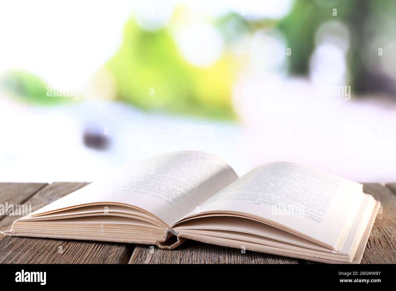 Open book on wooden table on natural background Stock Photo - Alamy