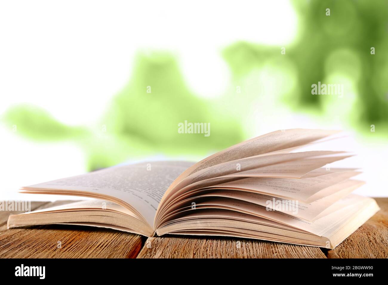 Open book on wooden table on natural background Stock Photo - Alamy