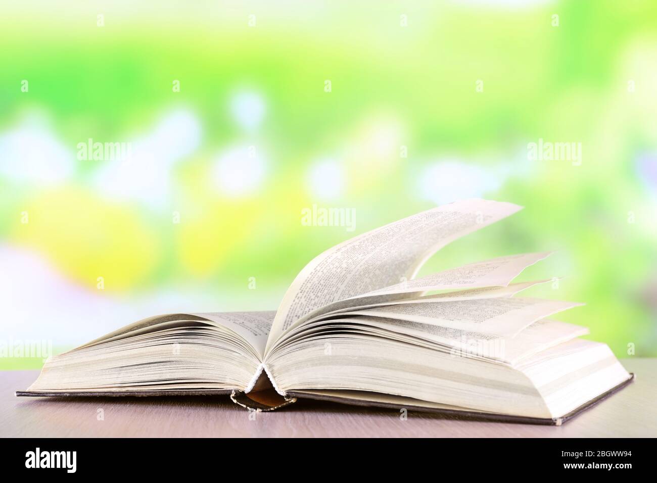 Open book on wooden table on natural background Stock Photo - Alamy