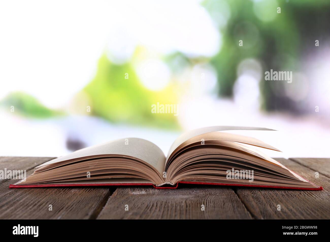 Open book on wooden table on natural background Stock Photo - Alamy