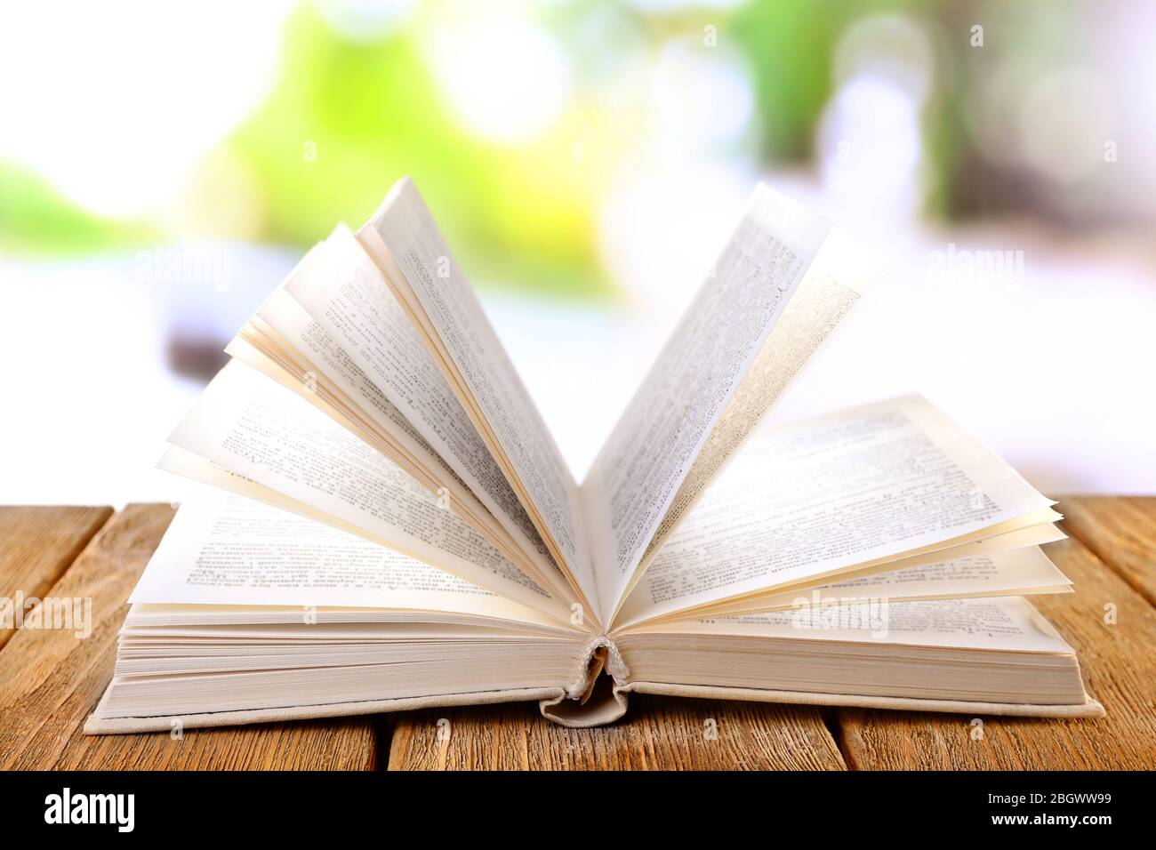 Open book on wooden table on natural background Stock Photo - Alamy