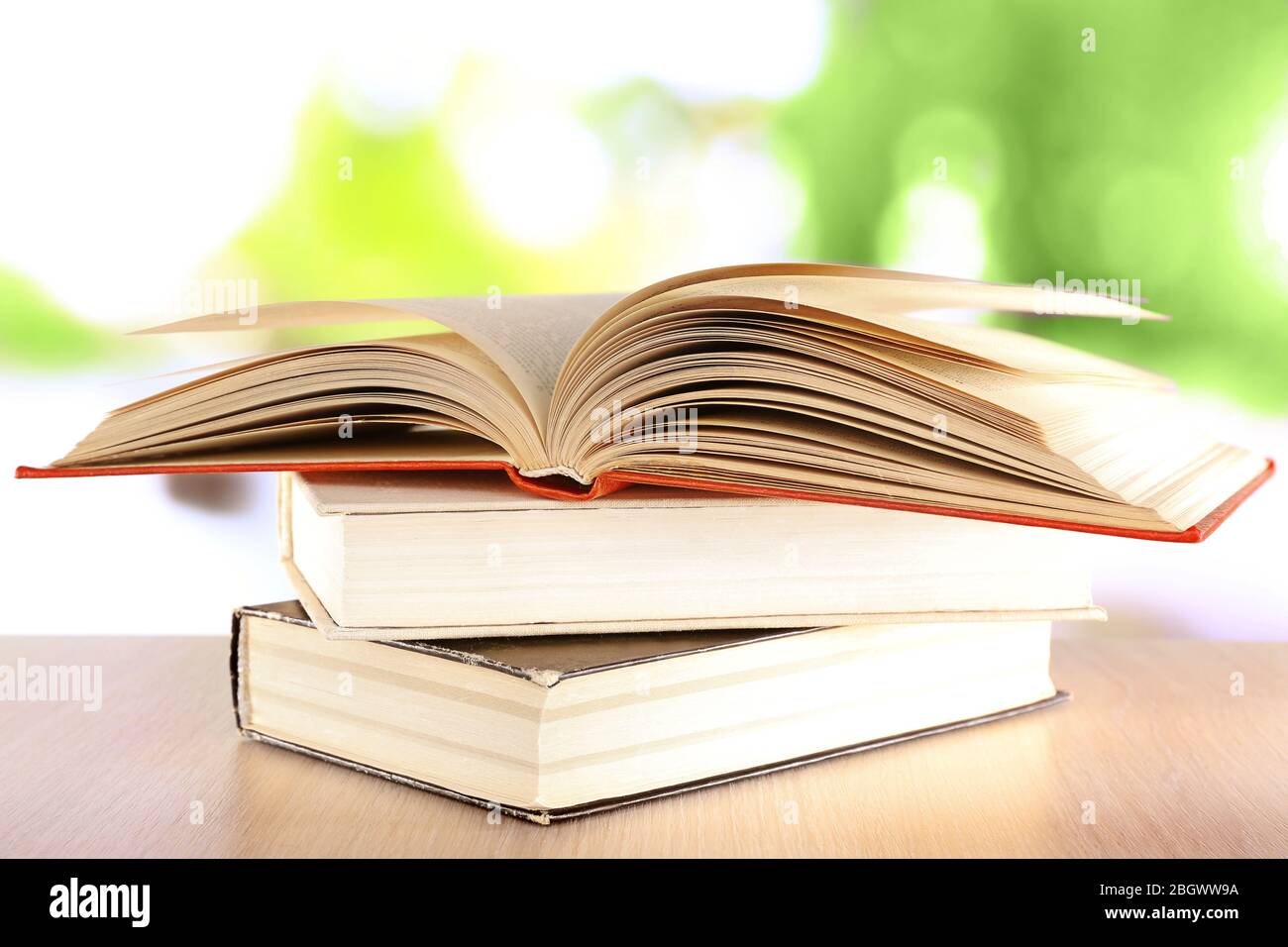 Books on wooden table on natural background Stock Photo - Alamy