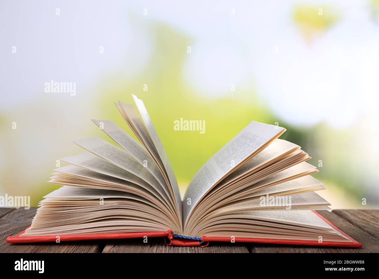 Open book on wooden table on natural background Stock Photo - Alamy
