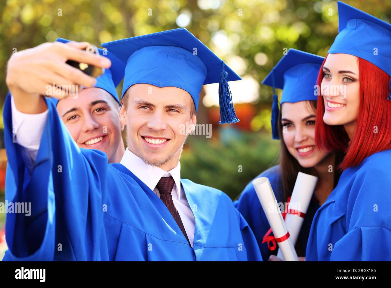 Graduate students wearing graduation hat and gown, outdoors Stock Photo ...