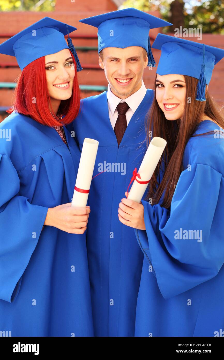 Graduate students wearing graduation hat and gown, outdoors Stock Photo ...