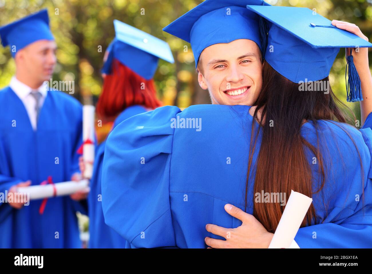 Graduate students wearing graduation hat and gown, outdoors Stock Photo ...