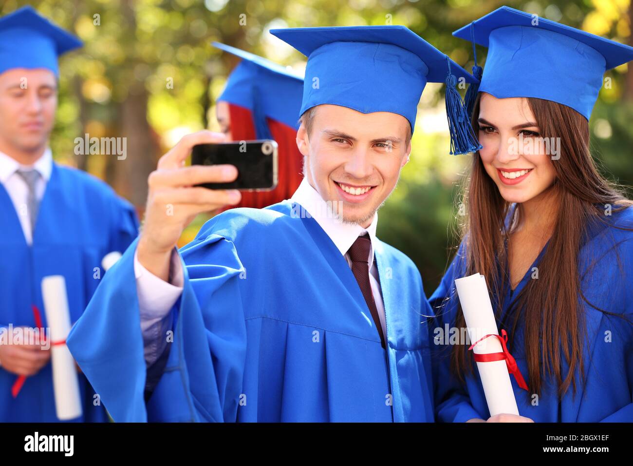 Graduate students wearing graduation hat and gown, outdoors Stock Photo ...