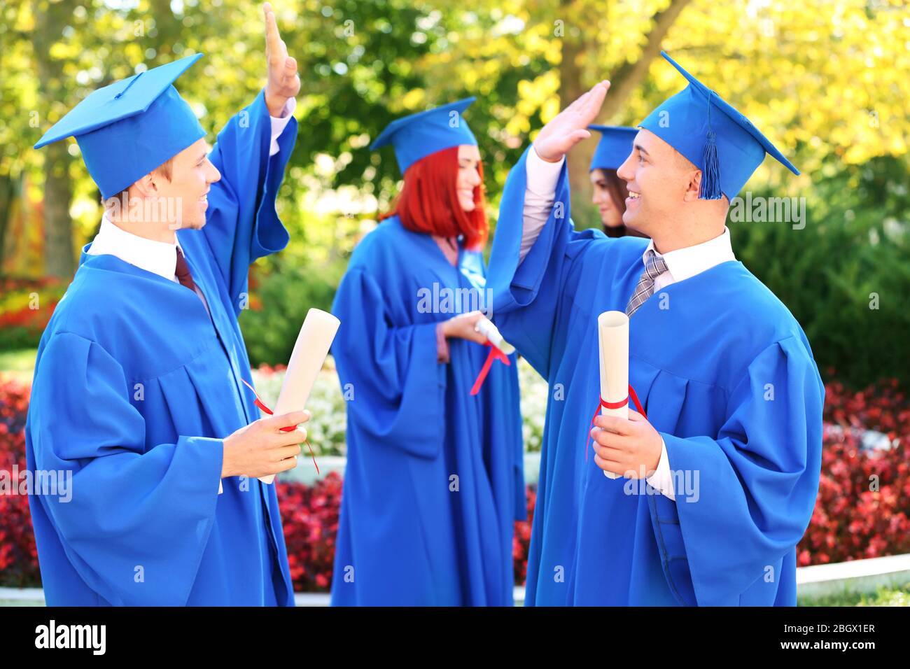 Graduate students wearing graduation hat and gown, outdoors Stock Photo ...