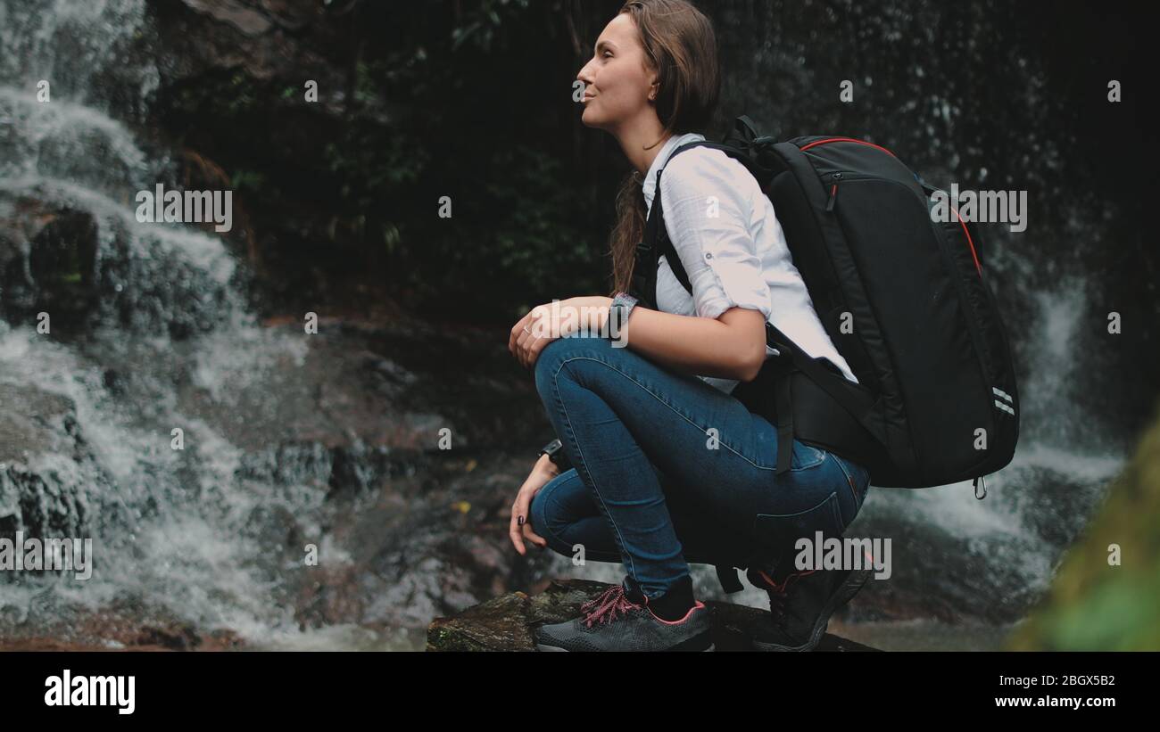 Woman Traveler Crouch near Splashing Waterfall. Fit Caucasian Girl with ...