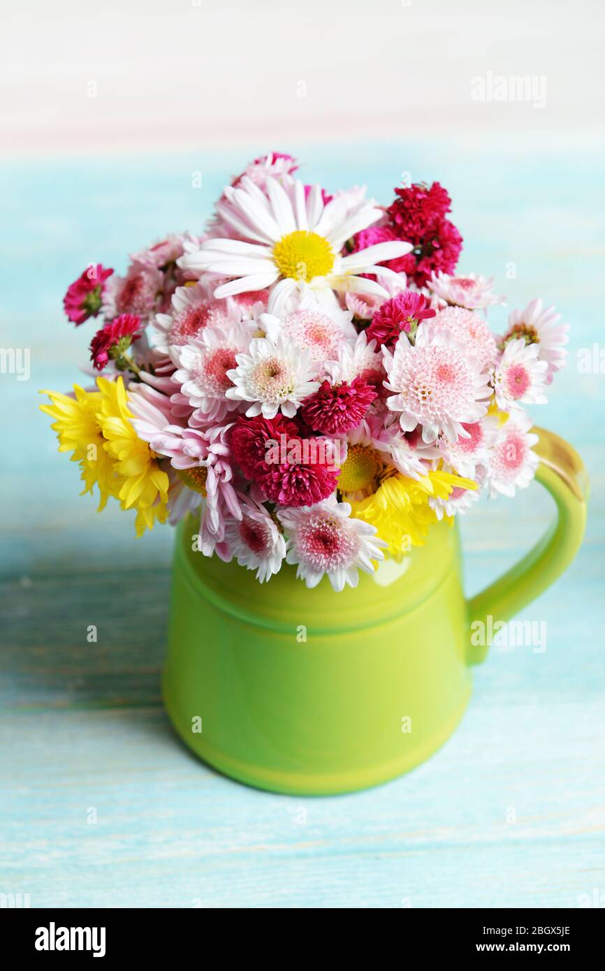 Beautiful flowers in pitcher on table on light background Stock Photo ...