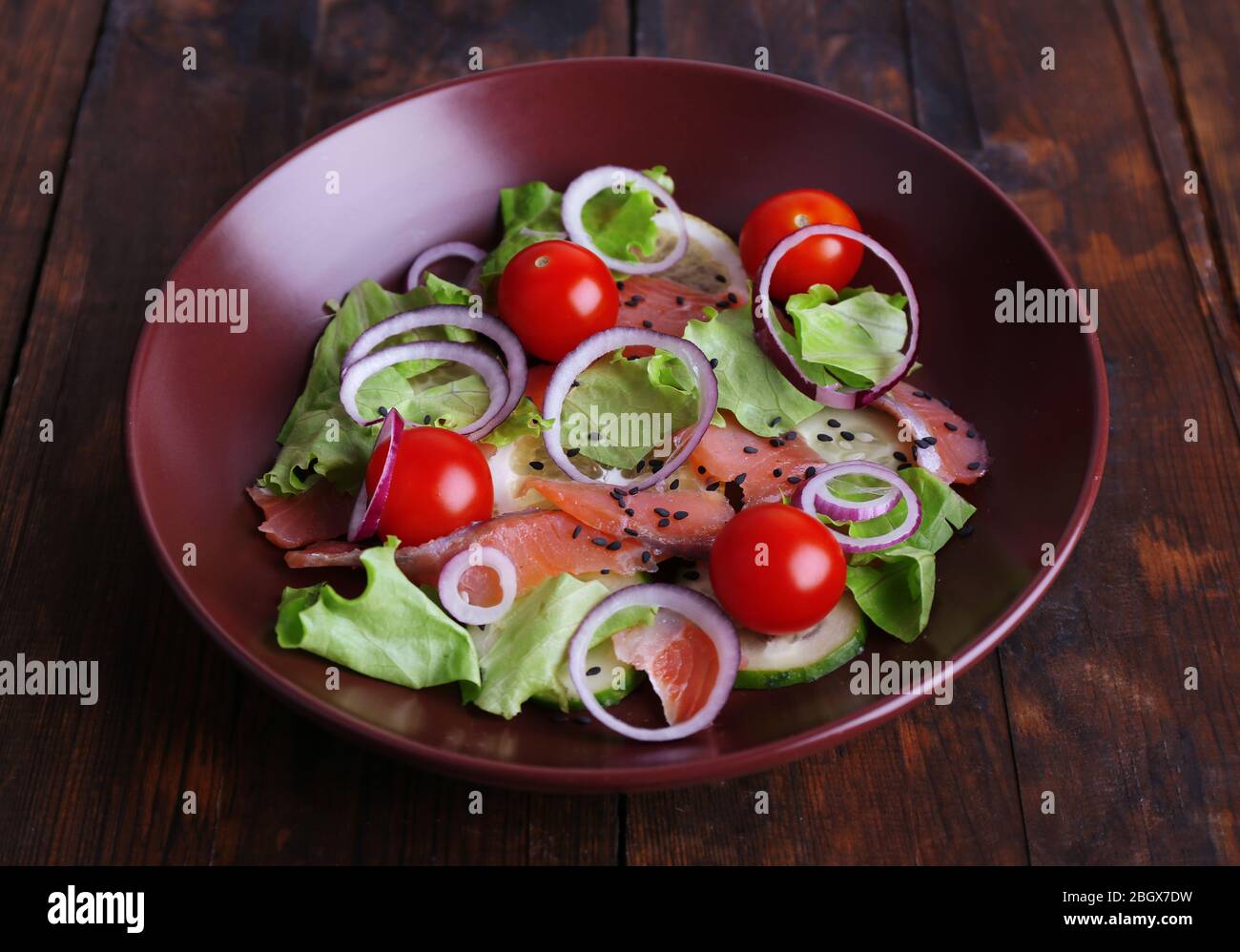 Fresh fish salad with vegetables on plate on wooden table close-up ...