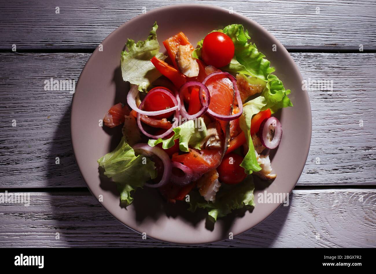 Fresh fish salad with vegetables on plate on wooden table close-up ...