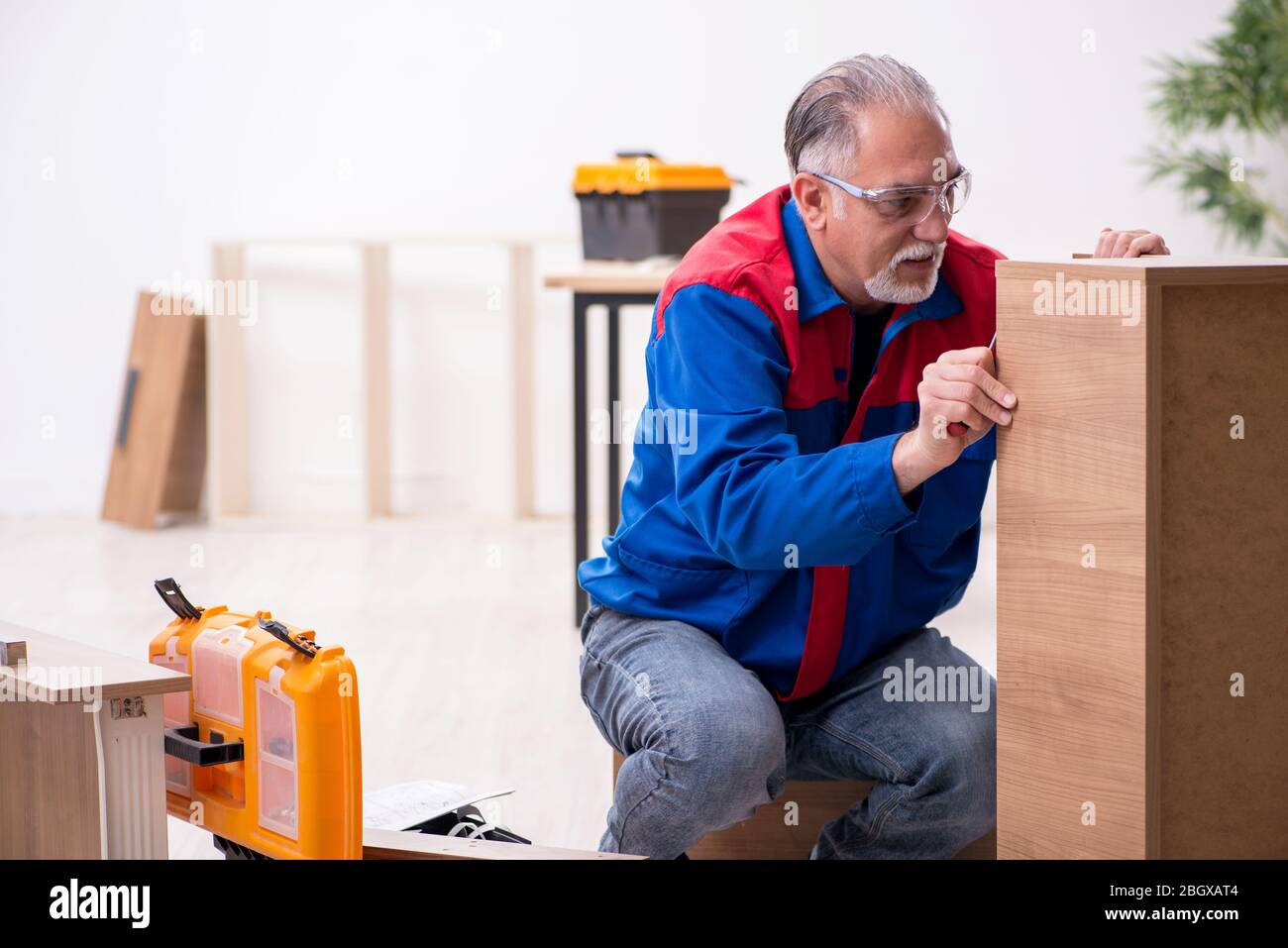 Old carpenter working indoors on furniture Stock Photo - Alamy