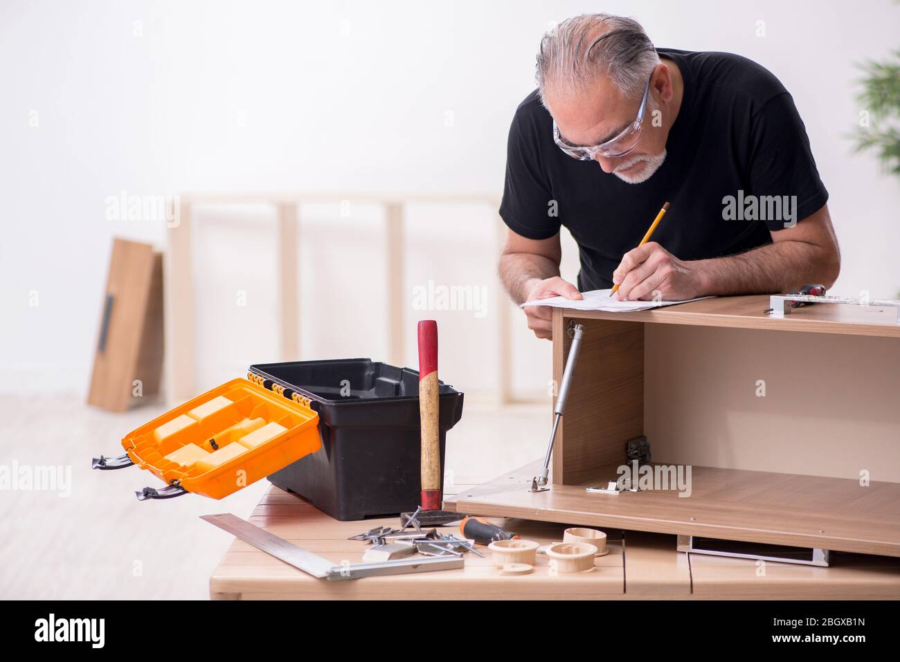 Old carpenter working indoors on furniture Stock Photo - Alamy