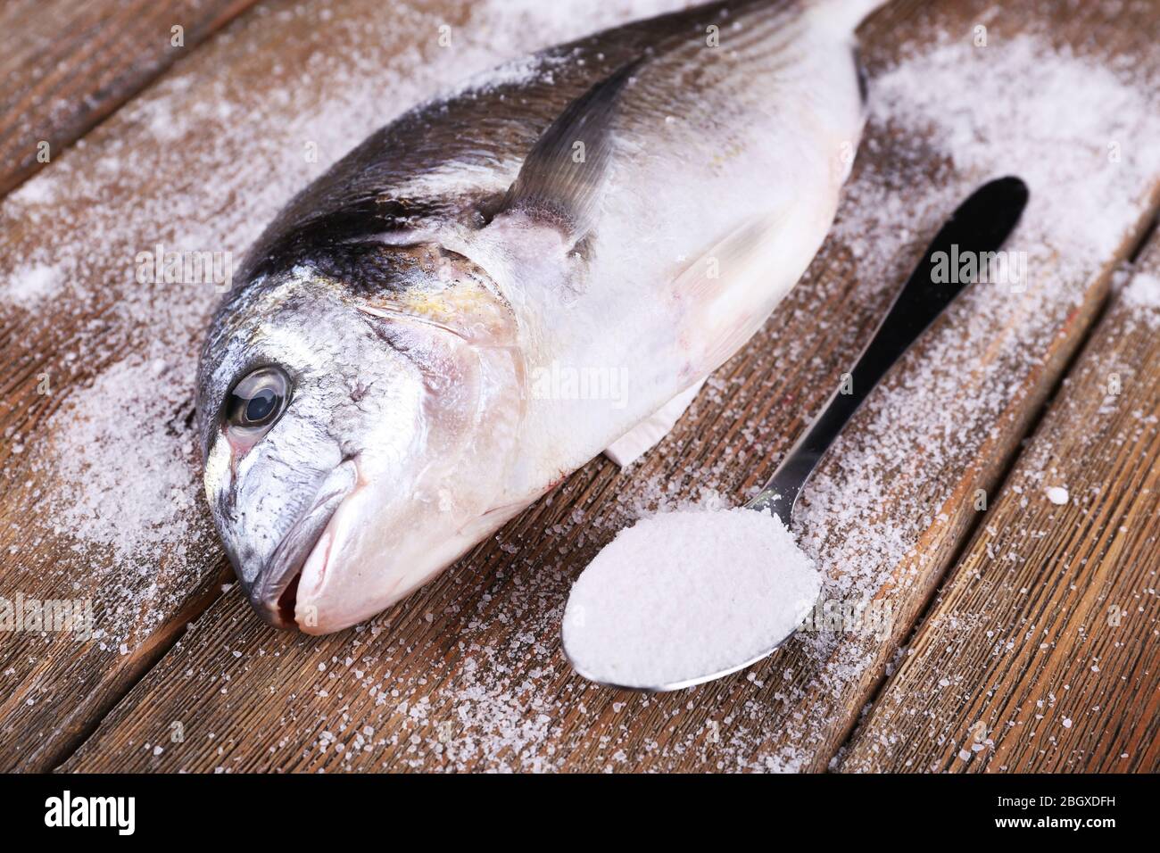 Fresh fish and salt in spoon on wooden background Stock Photo - Alamy