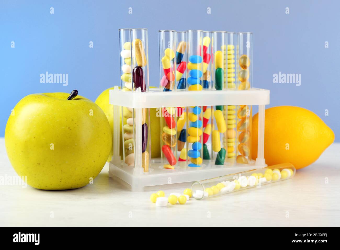 Different color drugs in test tubes and fruits, on wooden table, on ...