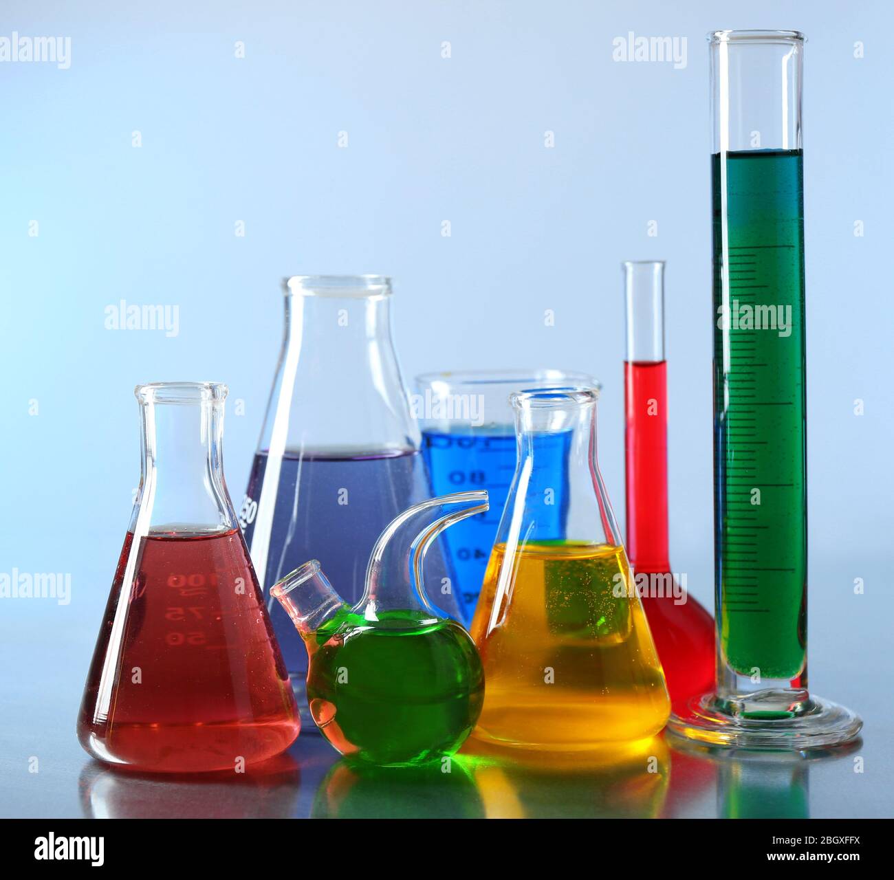 Different laboratory glassware with colorful liquid on color background ...