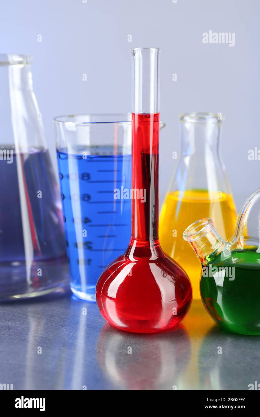 Different laboratory glassware with colorful liquid on color background ...