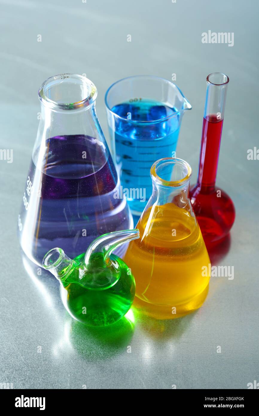 Different laboratory glassware with colorful liquid on color background ...