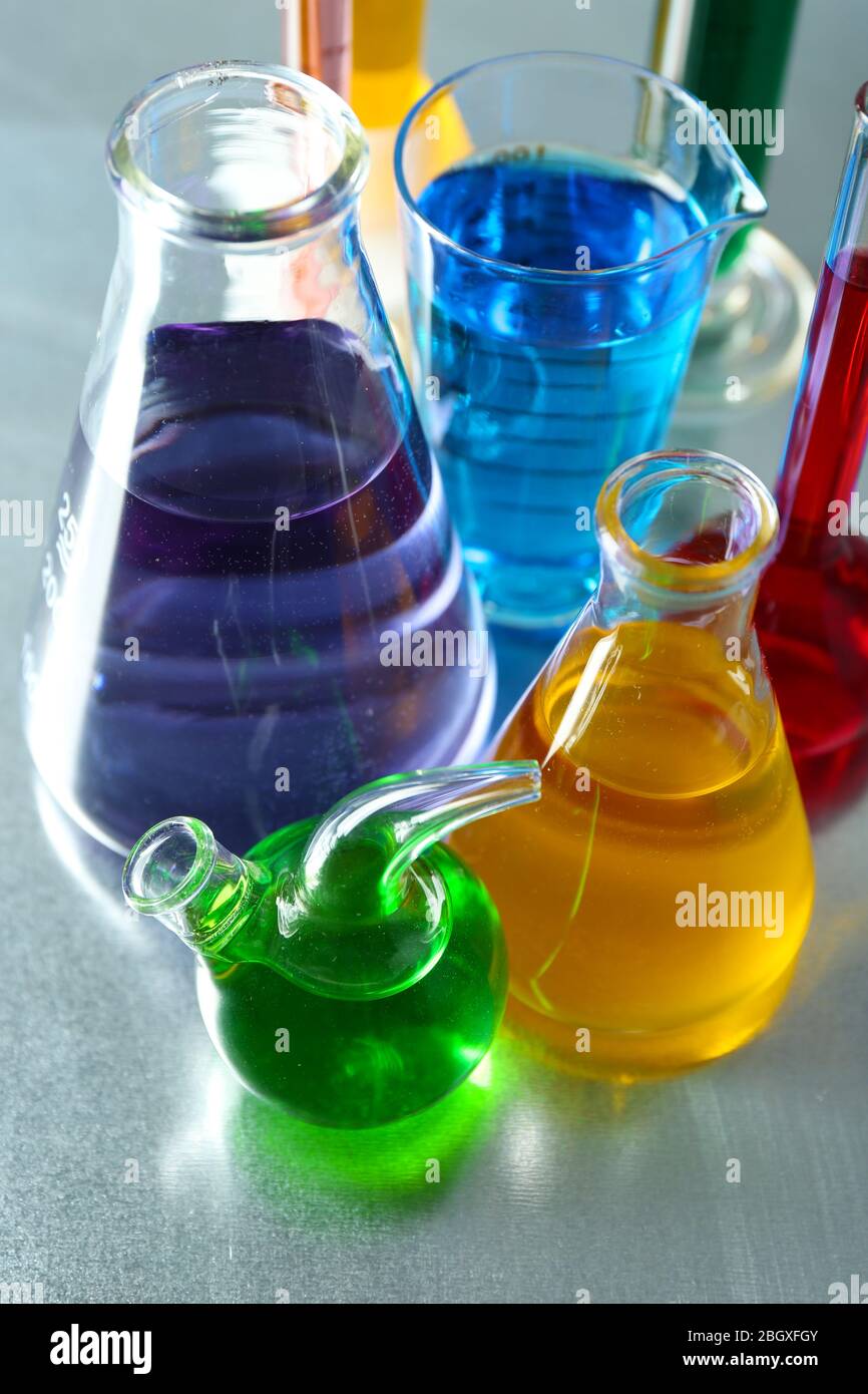 Different laboratory glassware with colorful liquid on color background ...