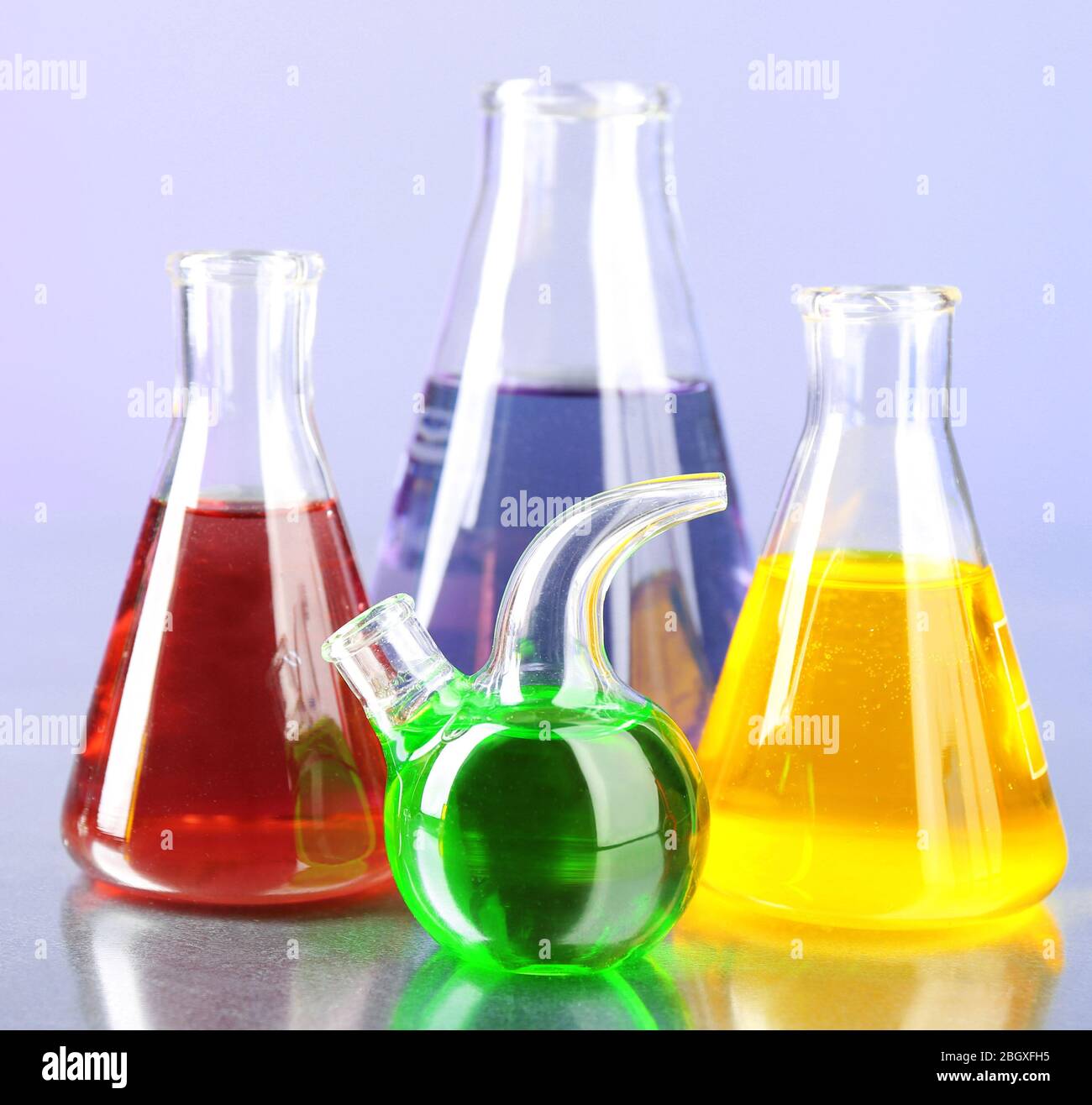 Different laboratory glassware with colorful liquid on color background ...