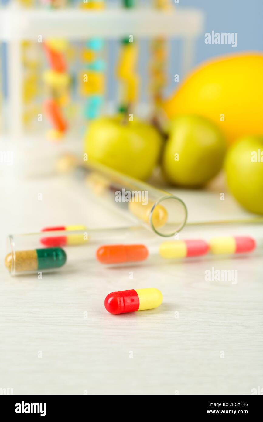 Different color drugs in test tubes and fruits, on wooden table, on ...