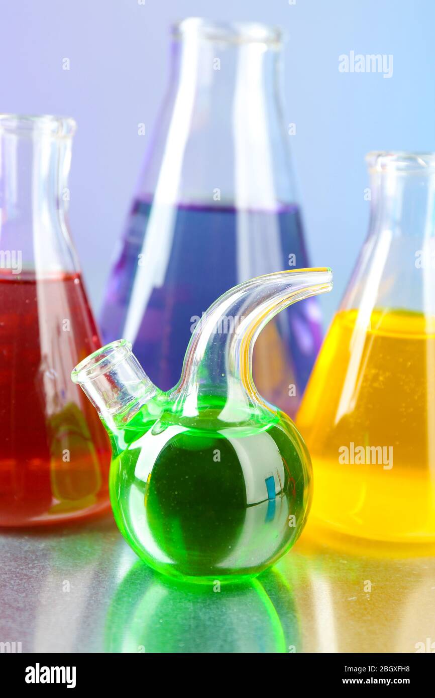 Different laboratory glassware with colorful liquid on color background ...
