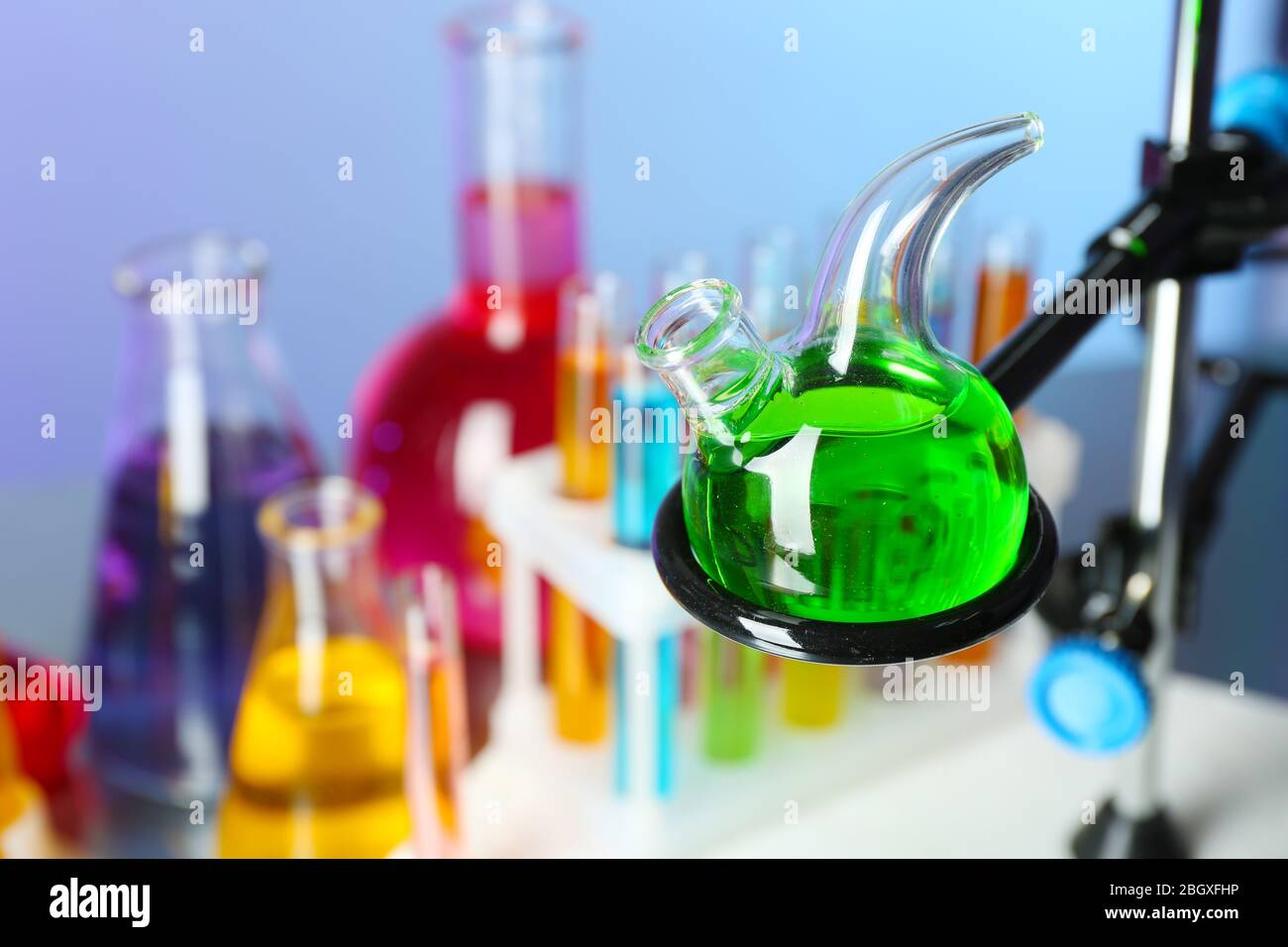 Different laboratory glassware with colorful liquid on color background ...