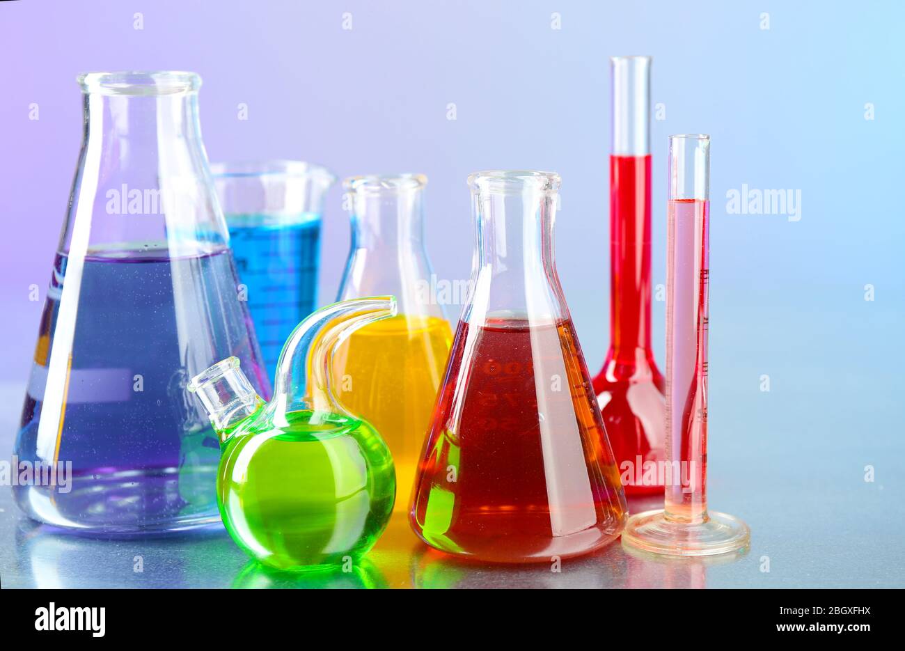 Different laboratory glassware with colorful liquid on color background ...