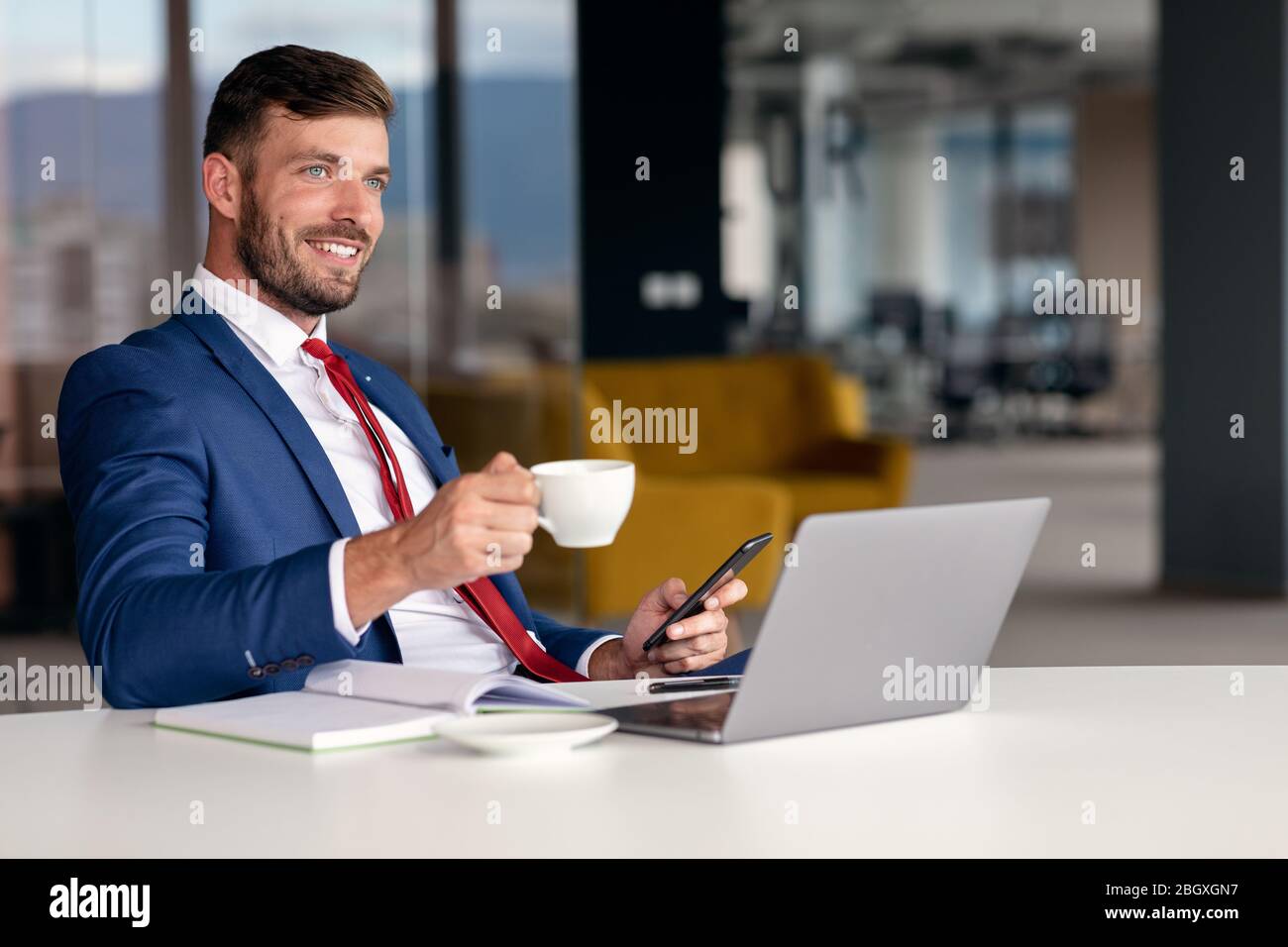 Portrait of young man sitting at his desk in the office Stock Photo - Alamy