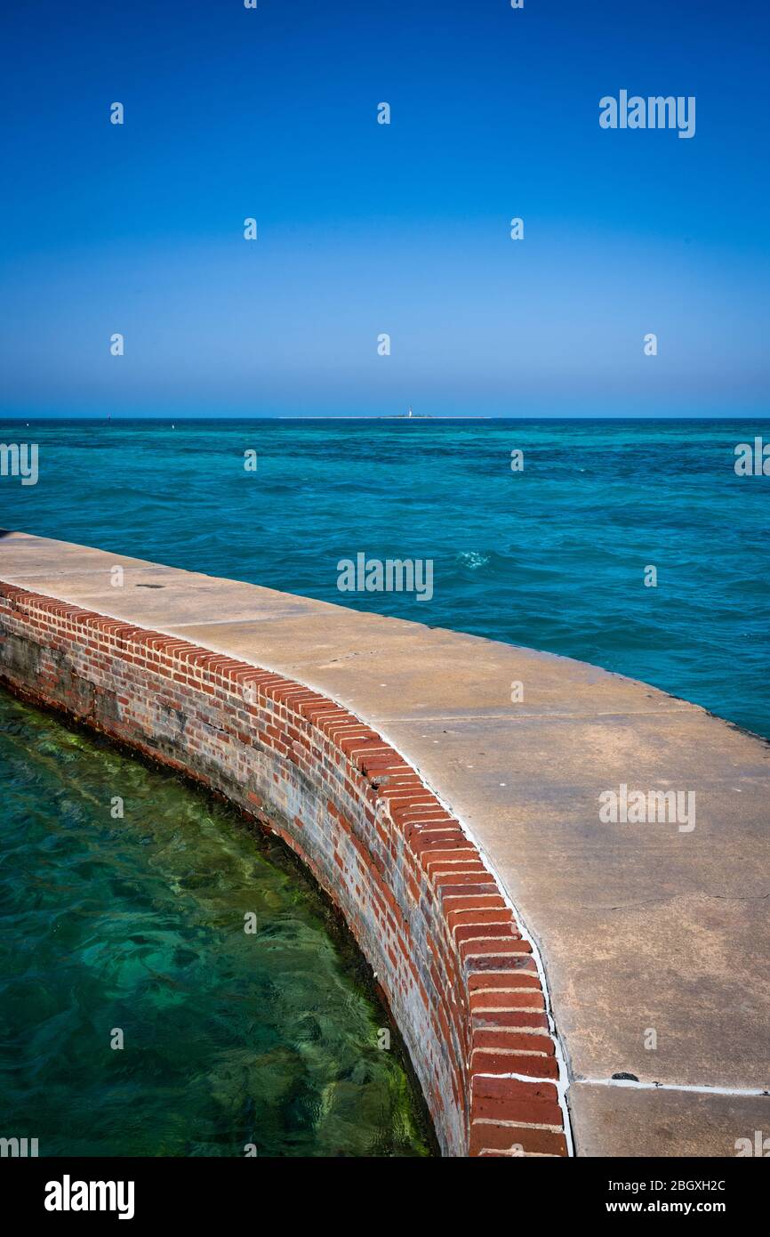 Dry Tortugas Mote Wall With Loggerhead Lighthouse in Distance on clear ...