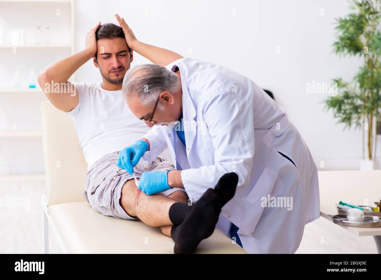 Leg injured man visiting doctor in first aid concept Stock Photo - Alamy