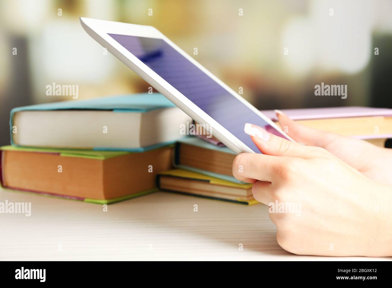 Female hand holding PC tablet near books, close-up. Modern education ...