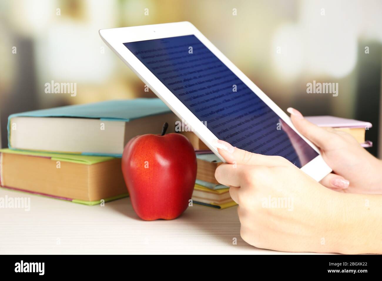 Female hand holding PC tablet near books, close-up. Modern education ...