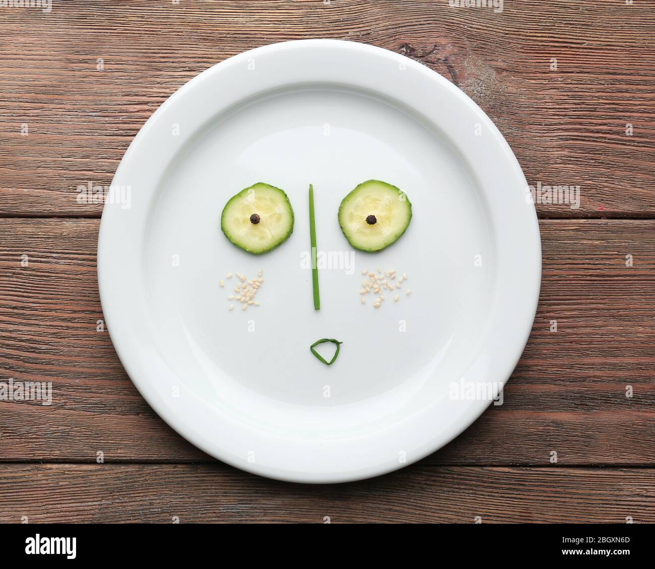 Vegetable face on plate on wooden table Stock Photo - Alamy