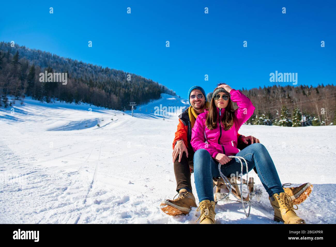 Young happy couple sledding in winter at ski center Stock Photo - Alamy