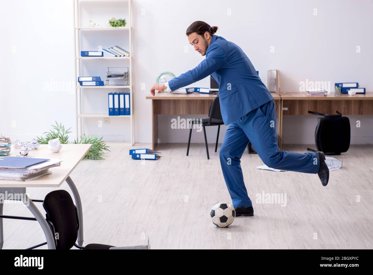Young employee playing football in the office Stock Photo - Alamy