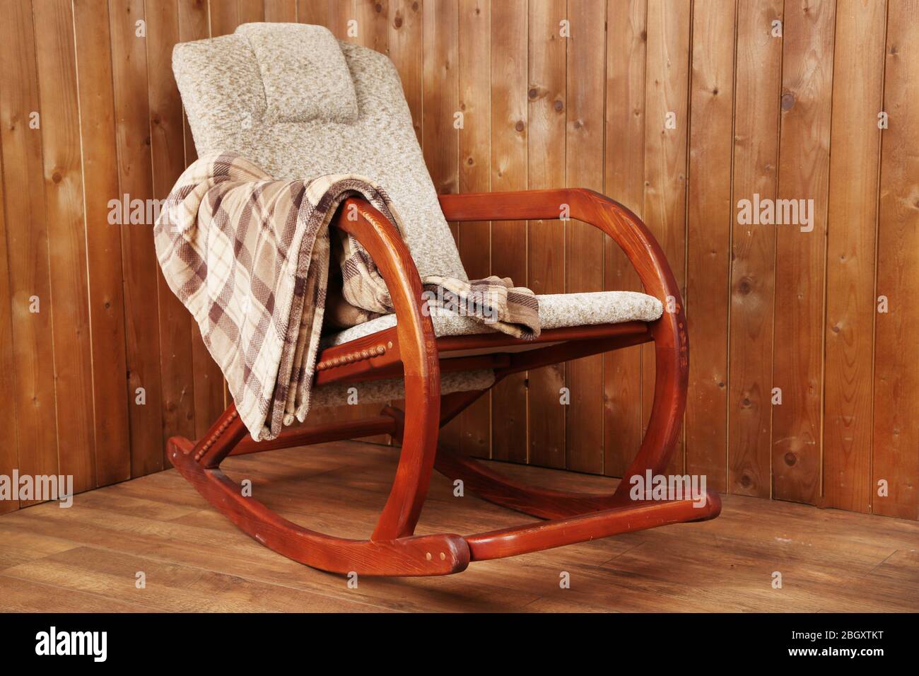 Rocking chair covered with plaid on wooden wall background Stock Photo ...