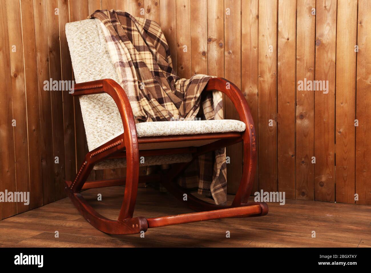 Rocking chair covered with plaid on wooden wall background Stock Photo ...