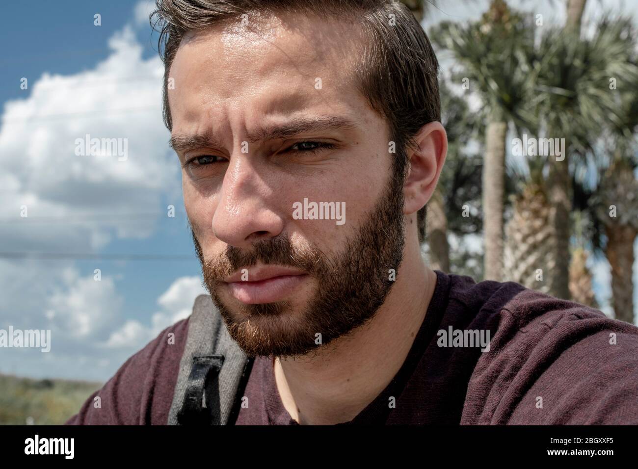 A close up of a man wearing a red shirt sits down feeling down in life ...
