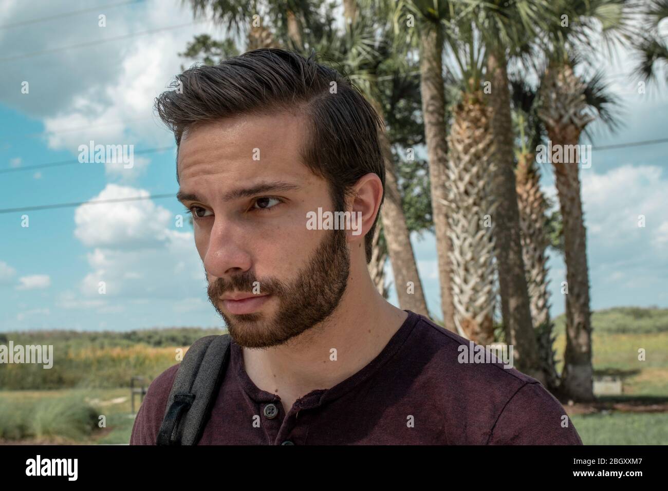 A close up of a man with natural blemished skin wearing a red shirt ...