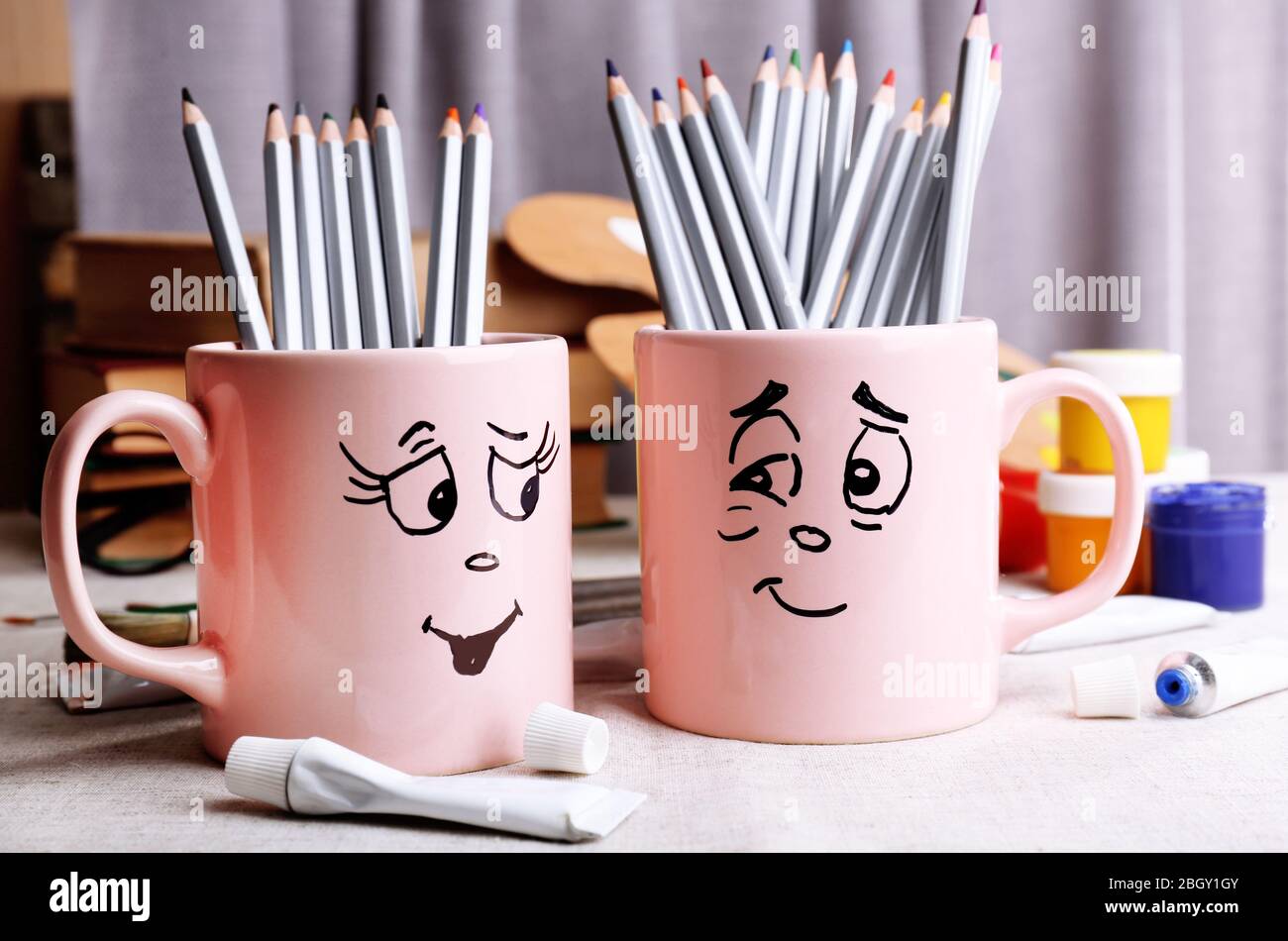 Emotional cups with pencils and paints on table Stock Photo - Alamy