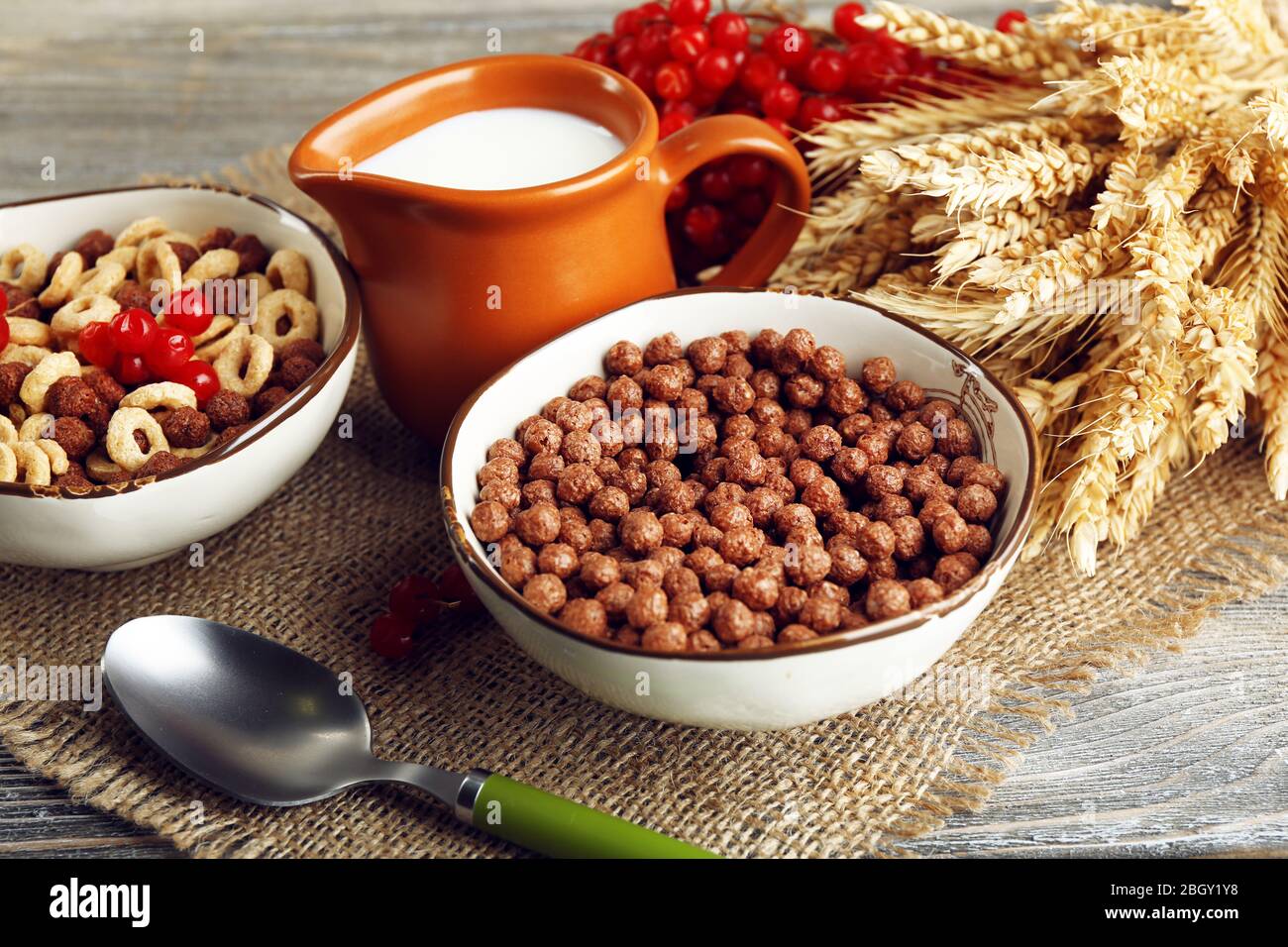 Various sweet cereals in ceramic bowls, fruits and jug with milk on ...
