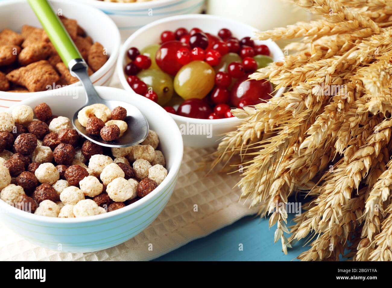 Various sweet cereals in ceramic bowls, fruits and jug with milk on ...