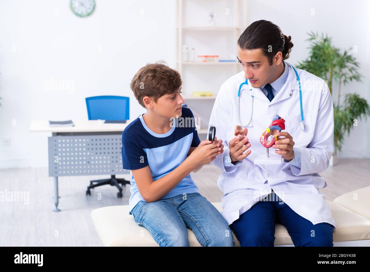 The young male doctor examining boy in the clinic Stock Photo - Alamy