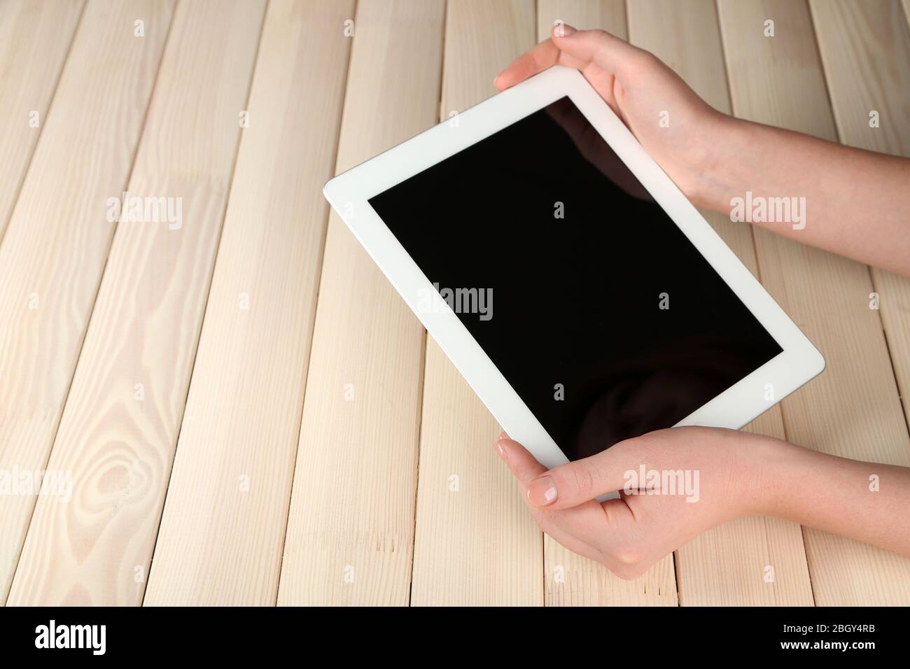 Hand using tablet PC on wooden table background Stock Photo - Alamy