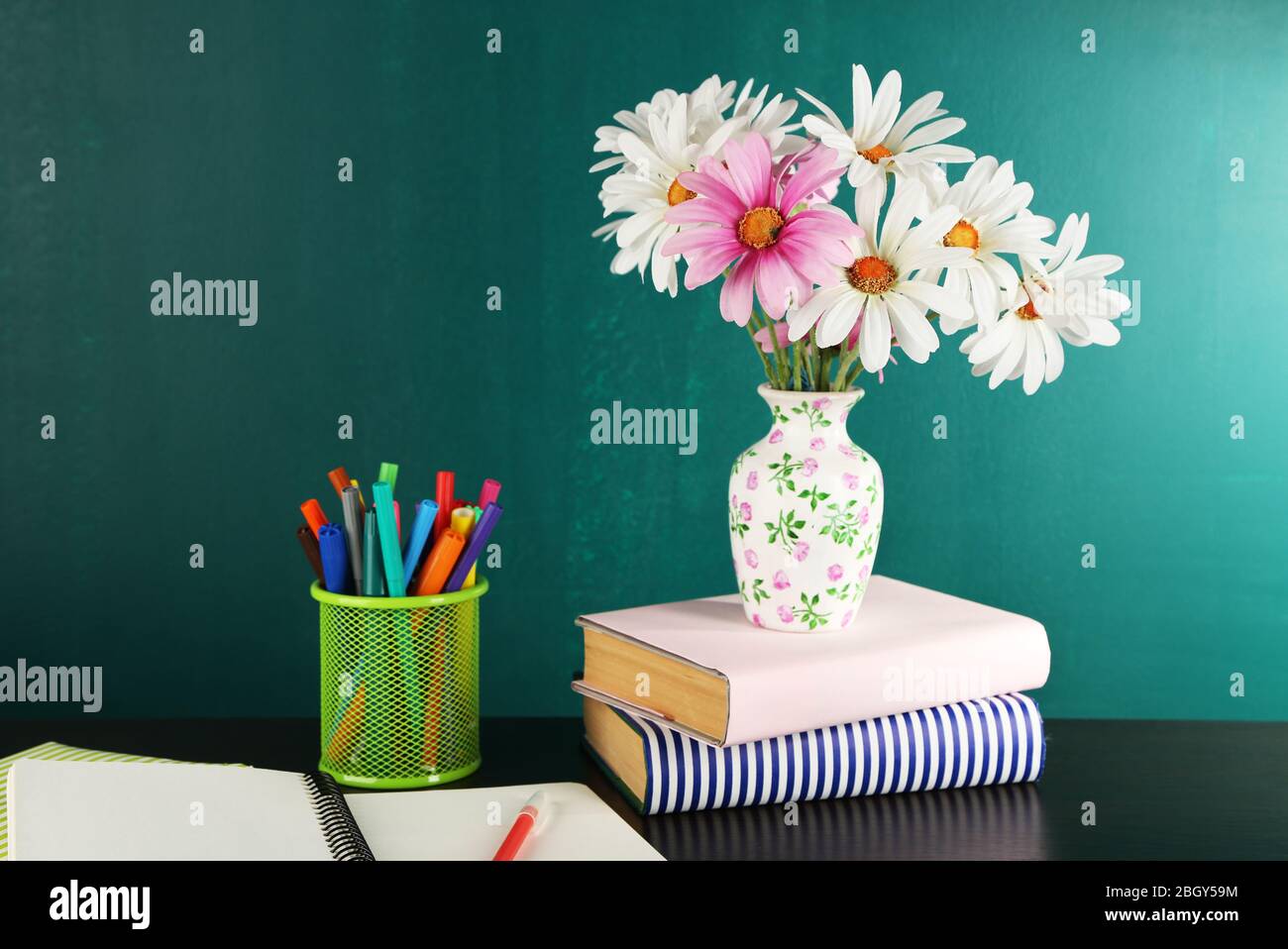 Composition on desk with books and flowers on green blackboard ...