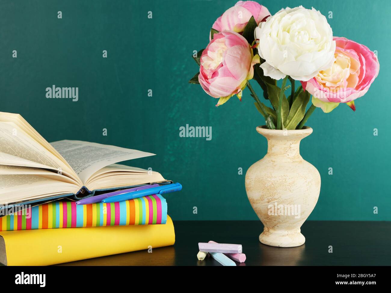 Composition on desk with books and flowers on green blackboard ...