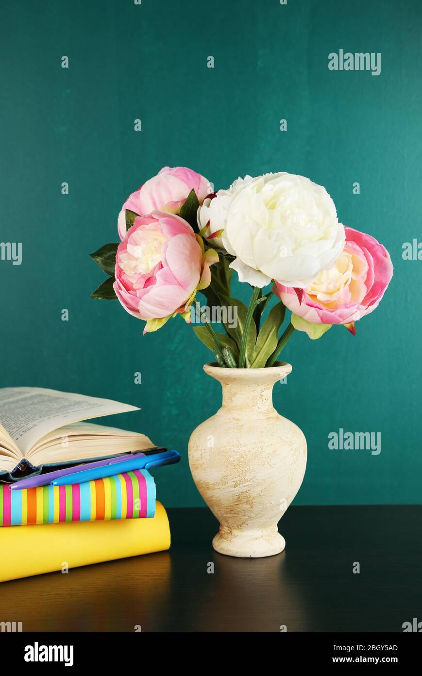 Composition on desk with books and flowers on green blackboard ...